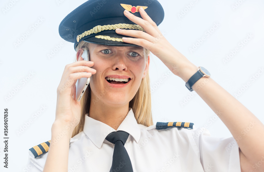 Shocked young female pilot receiving bad news while talking on mobile ...
