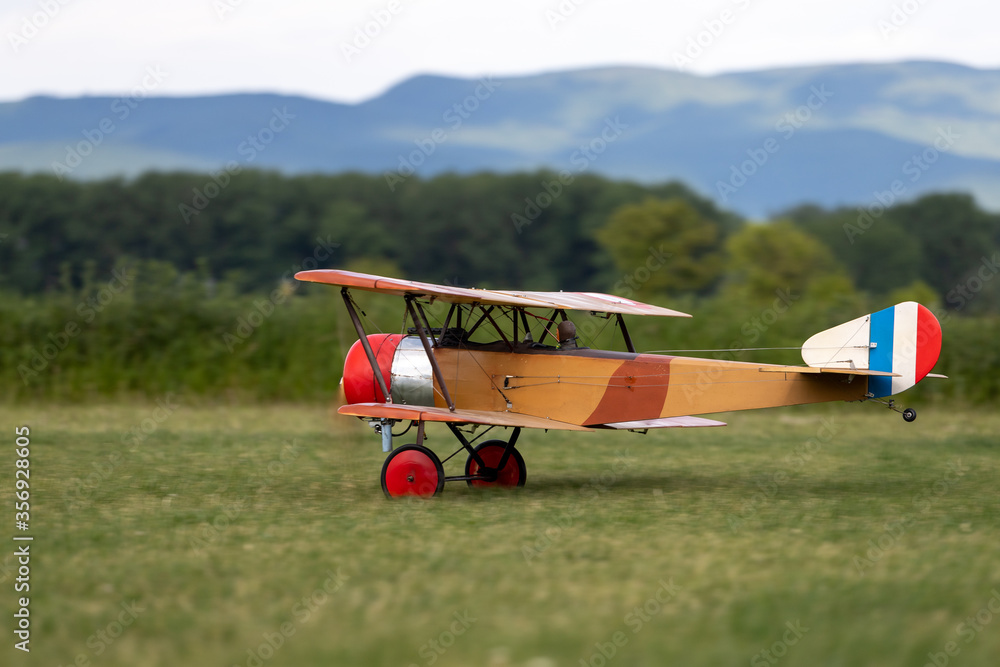 R/C biplane airplane landed on the grass with one wheel above the ...