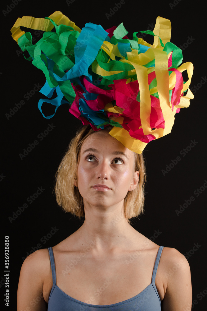 Colourful ribbons falling on the head of young girls in studio on black ...
