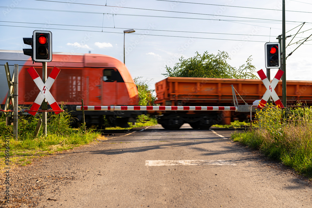 Closed barrier at a railway crossing with red warning lights on, a ...