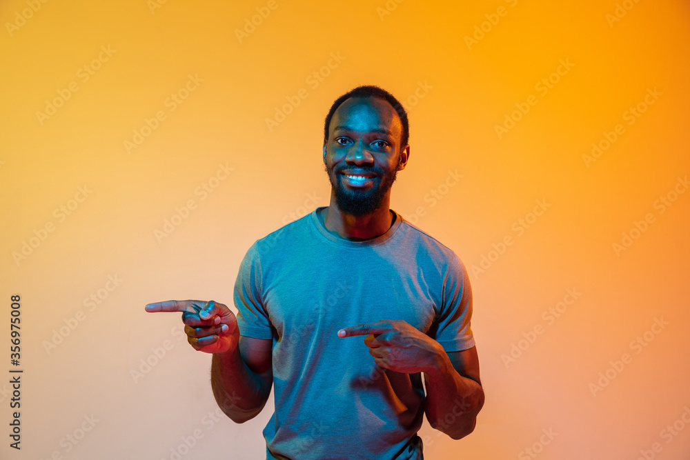 Pointing at side. African-american man's modern portrait on gradient ...