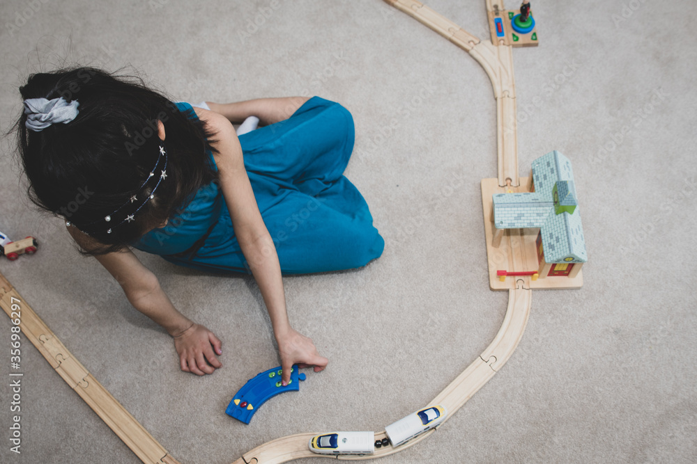 School age children building a wooden toy train track at home on the ...