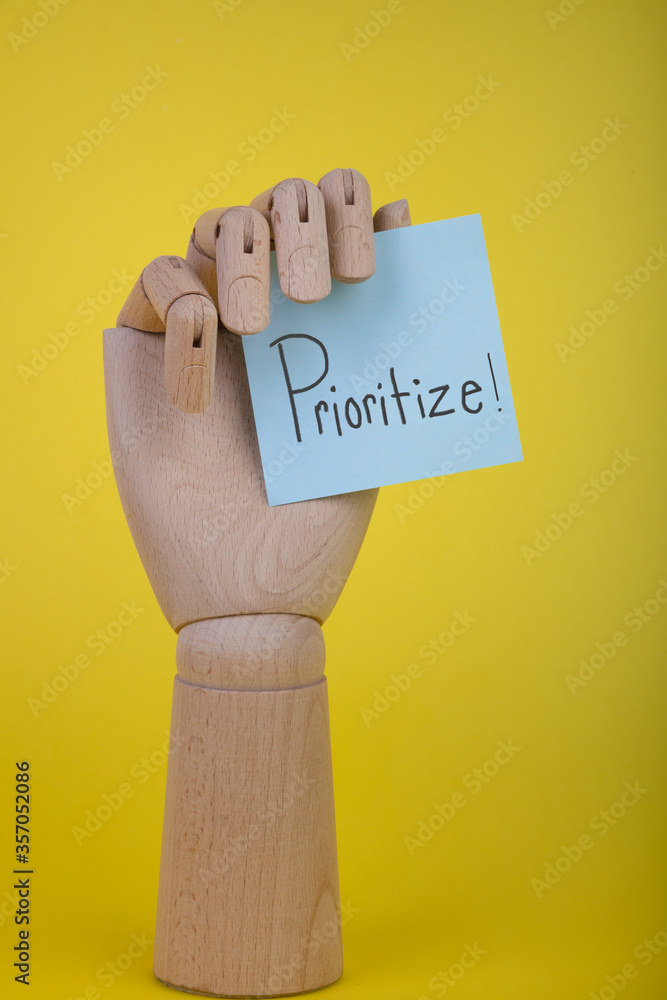 Fake wooden jointed hand holding a blue posted note with the word ...