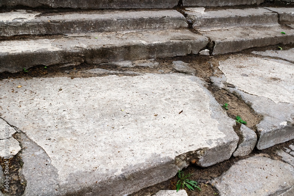 Old and dirty concrete steps with grass sprouting through the ground ...
