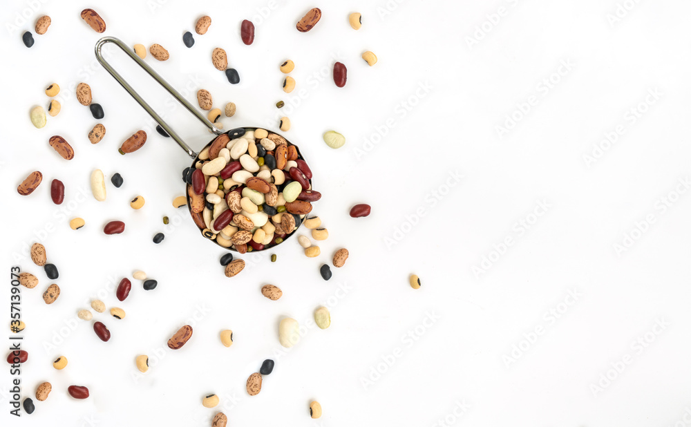 Isolated varieties of beans in stainless steel measuring cup on white ...