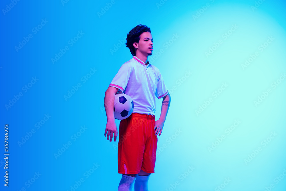 Leader. Football or soccer player on gradient blue studio background in ...