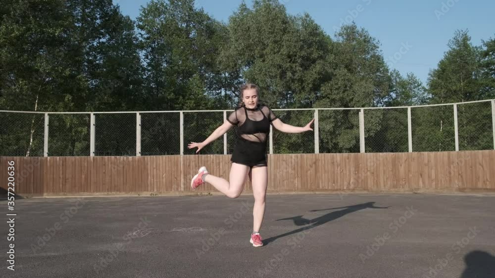 young woman dancer in a mesh T-shirt and black short shorts dancing ...