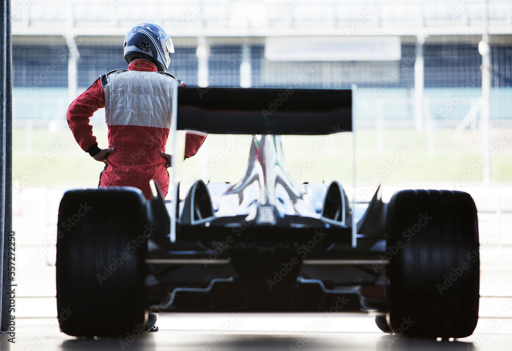 Racer standing with car in garage Stock Photo | Adobe Stock