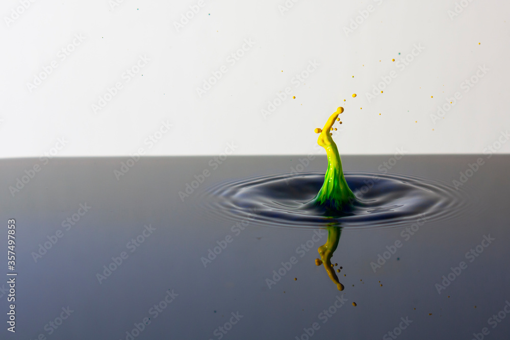 Splash of bright paint in still water. Drop of toxic yellow and green ...