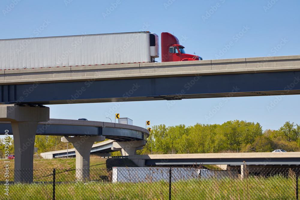 Large semi truck traveling over freeway bridge and interchanges near ...