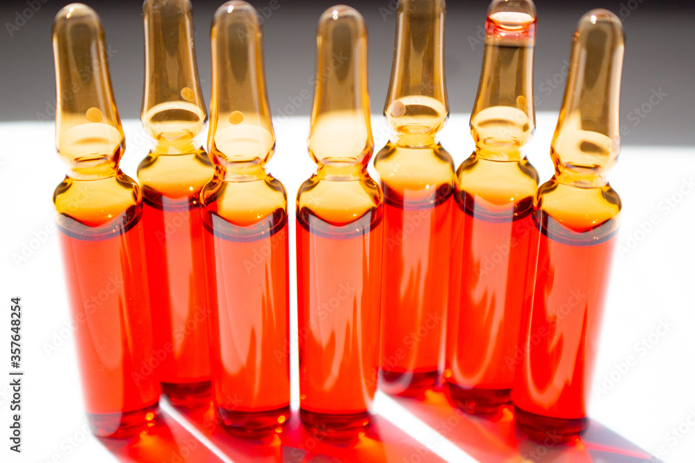 Seven red ampoules standing horizontally close-up on a white background ...