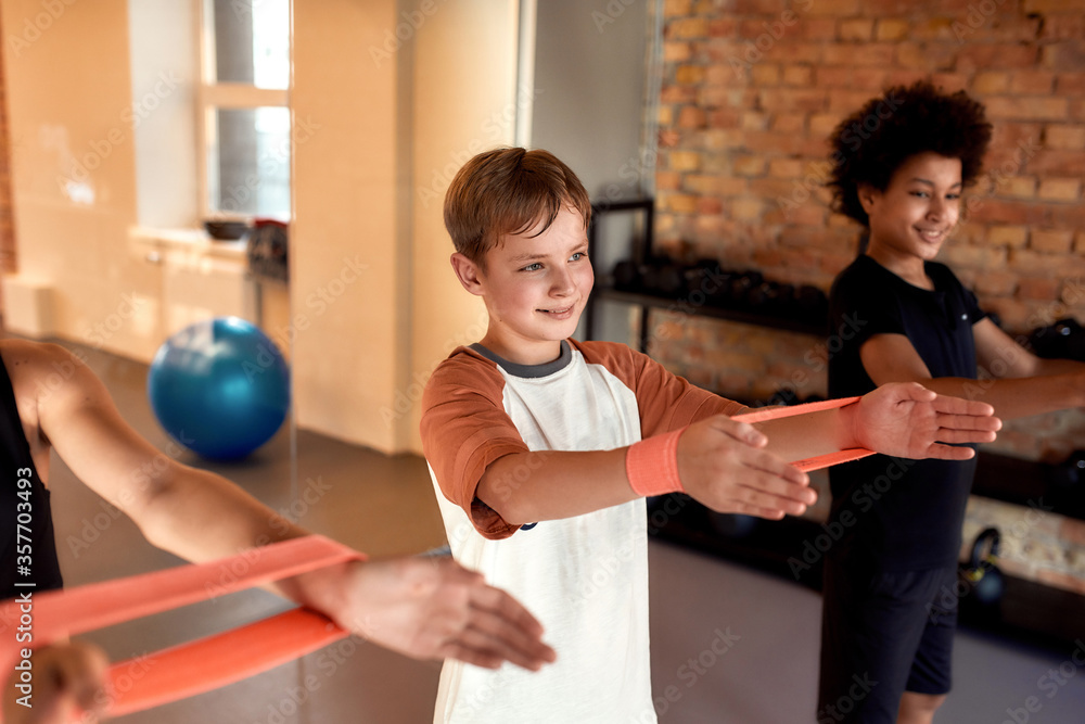 Caucasian boy working out using resistance band together with other ...
