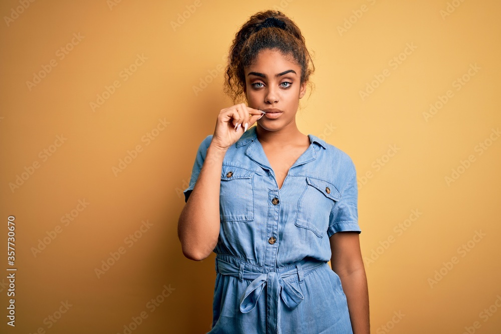 Young beautiful african american girl wearing denim dress standing over ...