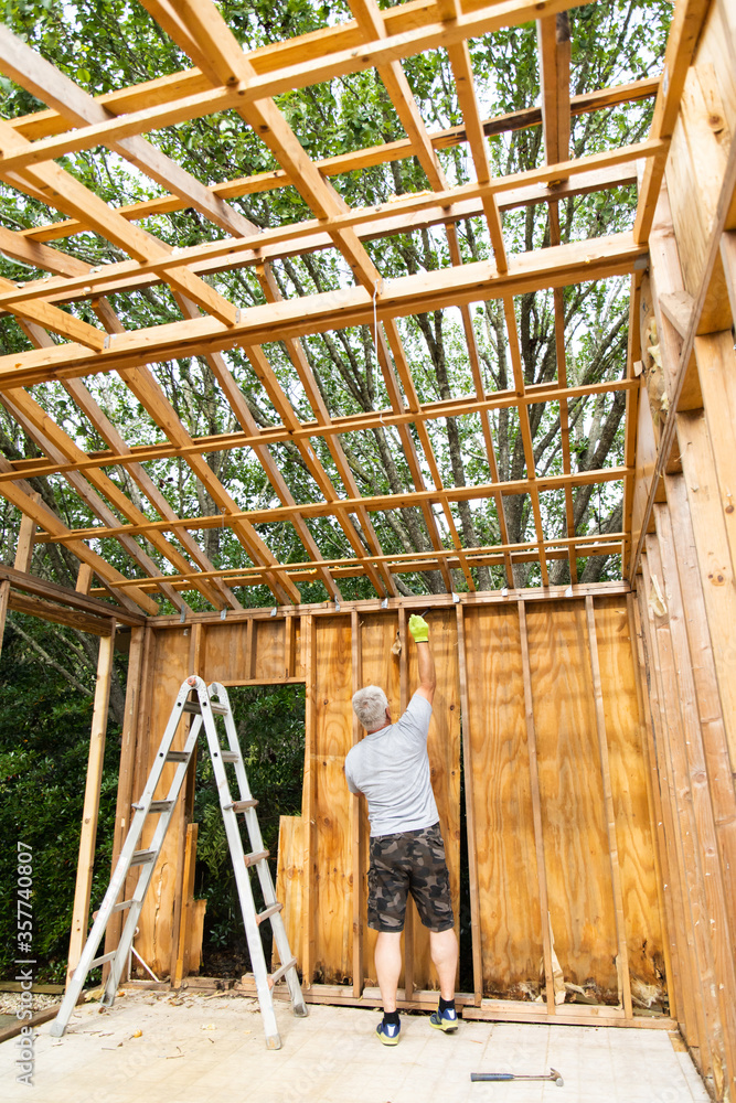 Demolition phase with a man tearing down an old shed with a crowbar in ...