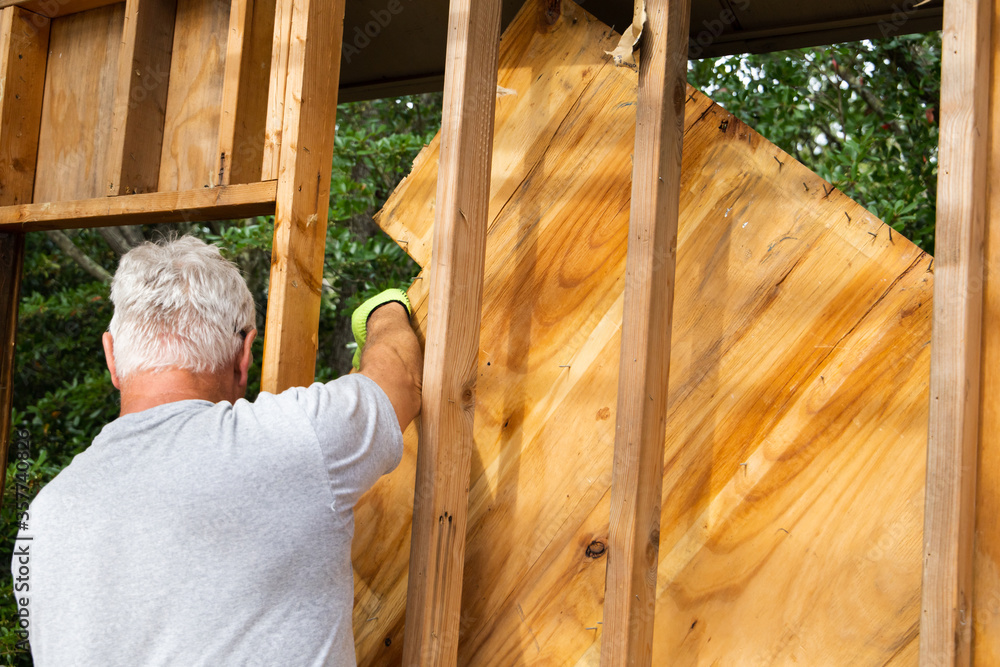 Demolition phase with a man tearing down an old shed in a backyard that ...
