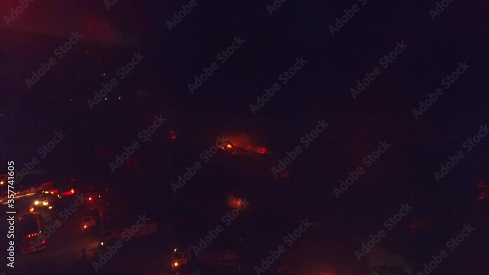 Aerial 4k view of a building on fire, firefighters fighting the flames ...
