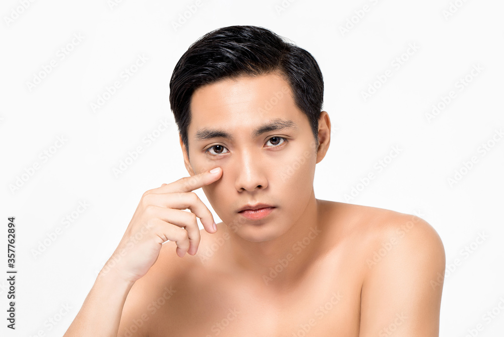 Handsome young Asian man touching under eye skin isolated on white ...