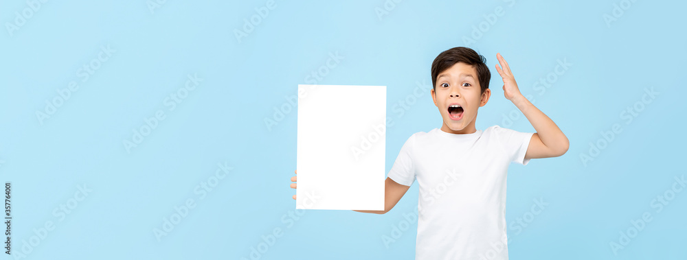 Cute little boy holding empty paper being shocked and gasping on light ...