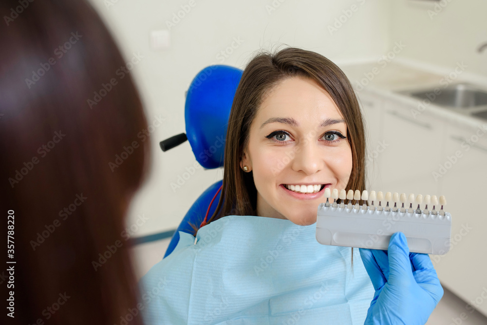 The dentist is checking the color with the tooth color chart of the ...