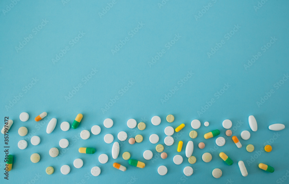 Colorful pills and capsules on a blue green background, tablets are ...