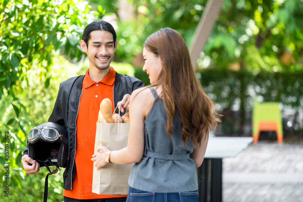 Delivery man in orange uniform pick up food for delivery at restaurant ...