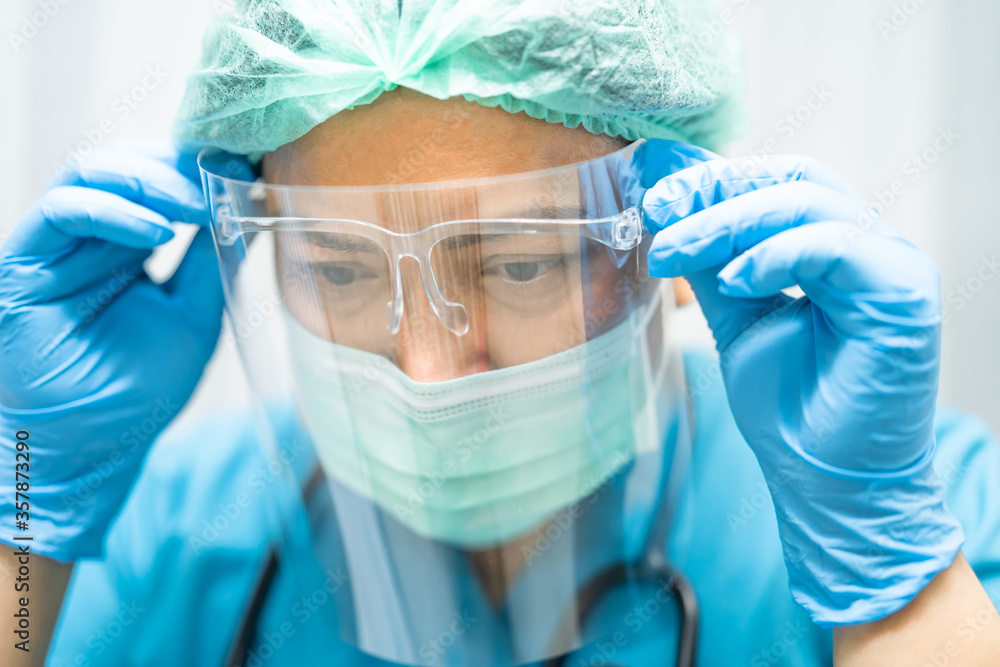 Asian doctor wearing face shield and PPE suit to check patient protect ...