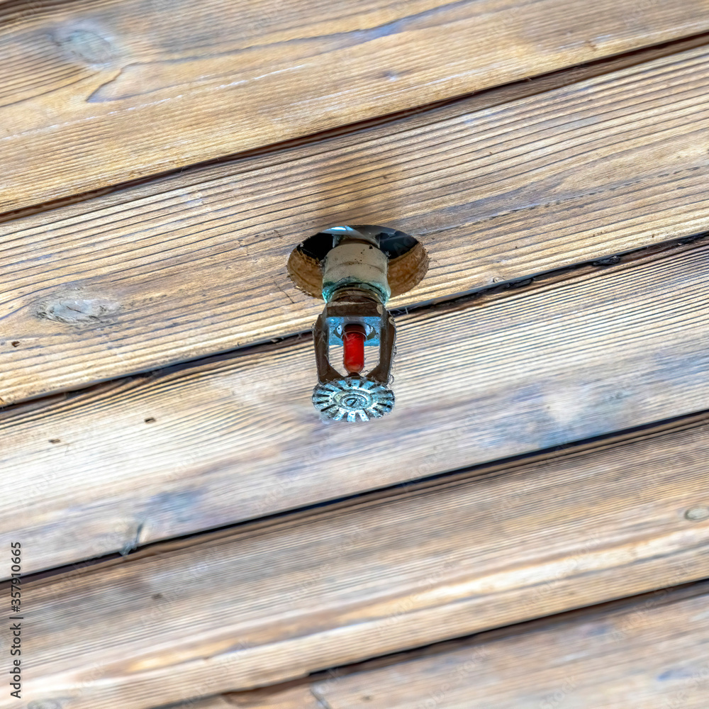 Square Fire sprinkler head installed on the brown wooden ceiling of a ...