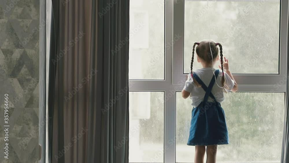 Stockvideon slow motion back side view little girl stands near window ...