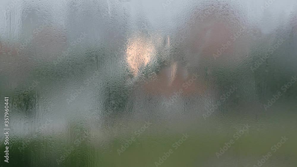 rapid flow of rain drops falling on the glass, moving raindrops on the ...
