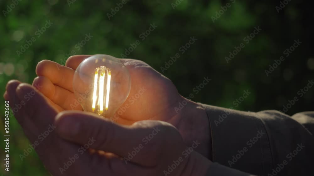 idea solar energy in nature, hand holding light bulb. Eco energy saving ...