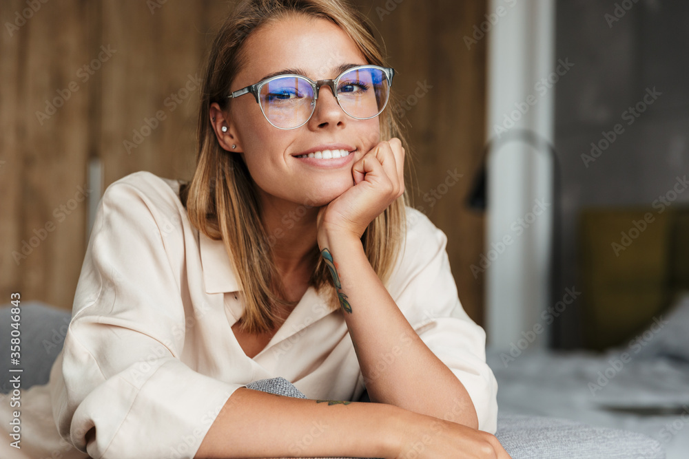 Image of woman smiling and looking at camera while sitting on couch ...