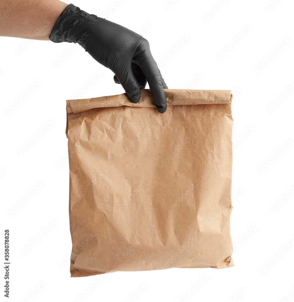 hand in a black latex glove holds a full paper bag of brown craft paper ...