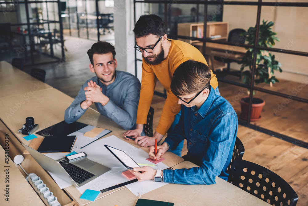 Group of male partners cooperating together in workspace sitting at ...