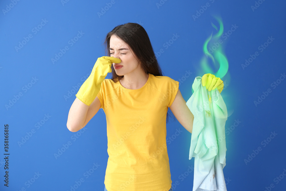 Displeased young woman with dirty stinky clothes pinching her nose on ...