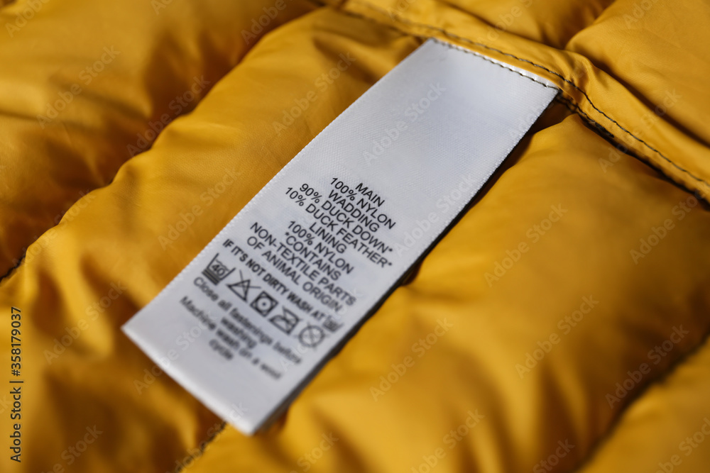 Clothing label with care symbols and material content on yellow jacket ...