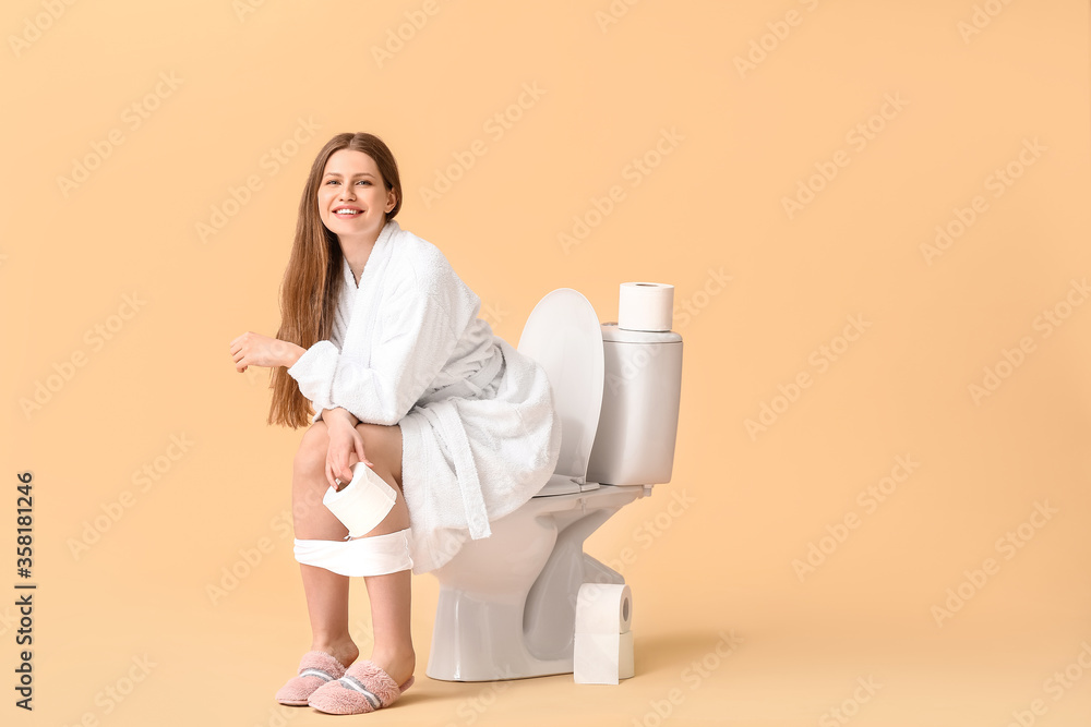 Young woman sitting on toilet bowl against color background Photos ... Young woman sitting on toilet bowl against color background Photos ...