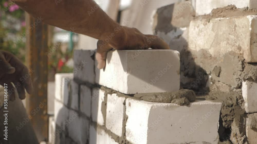 Construction worker or mason laying bricks and creating walls ...