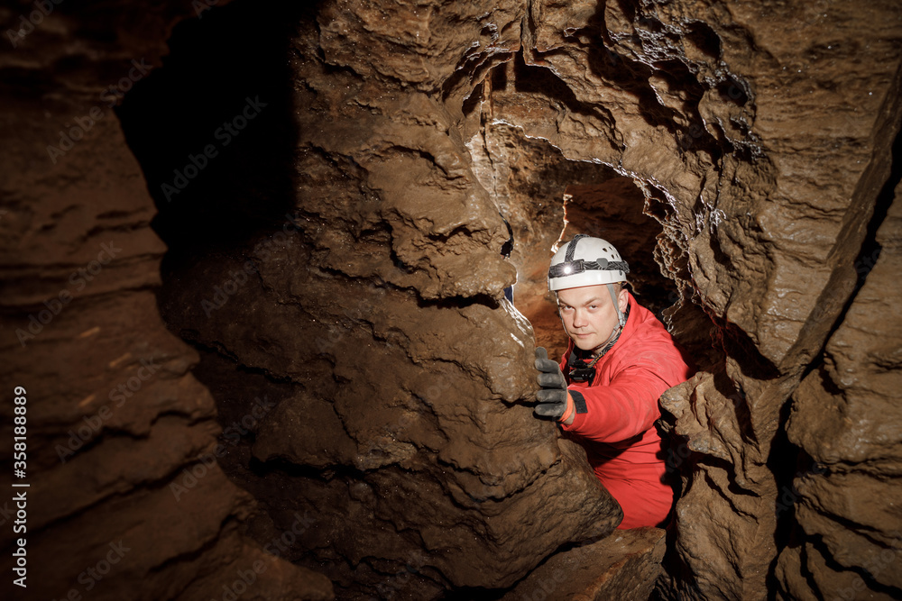 Man walking and exploring dark cave with light headlamp underground ...