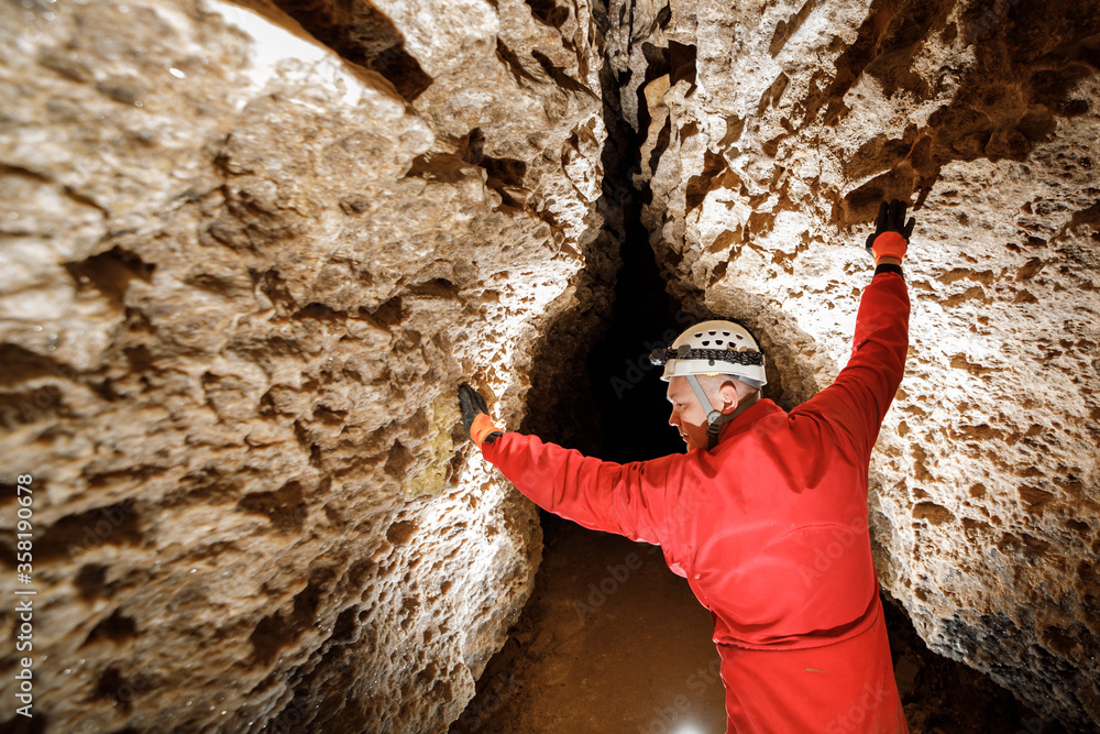 Man walking and exploring dark cave with light headlamp underground ...