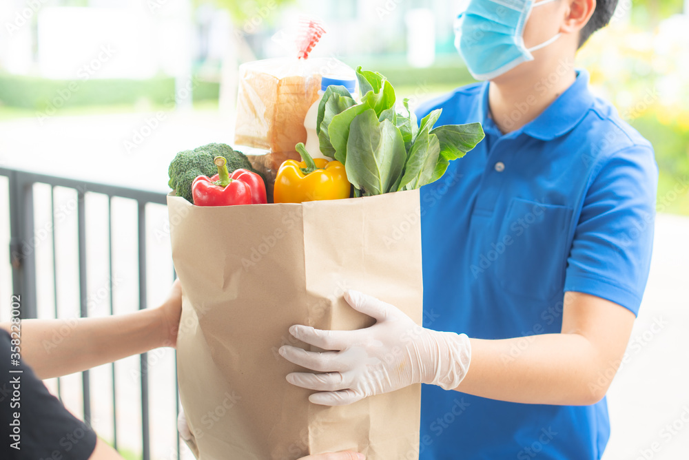 Deliver man wearing medical gloves and face mask in uniform handling ...