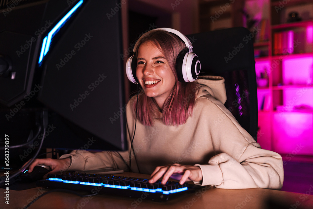 Image of excited girl smiling and playing video game on computer Stock ...