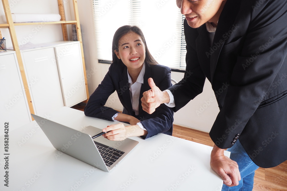 Boss giving thumbs up to his female colleague at work On the job ...