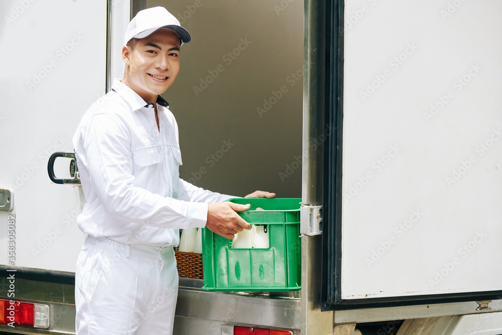 Horizontal medium shot of Asian milkman wearing white clothes putting ...