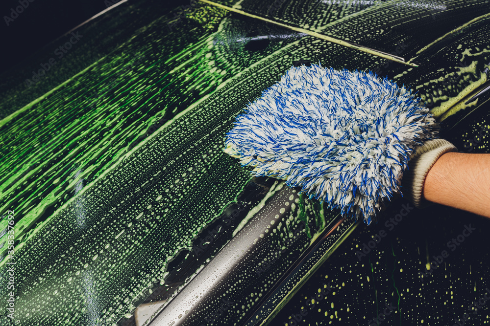 Car wash by hand. Soap suds, bubbles and mitt. Man washing a car by ...