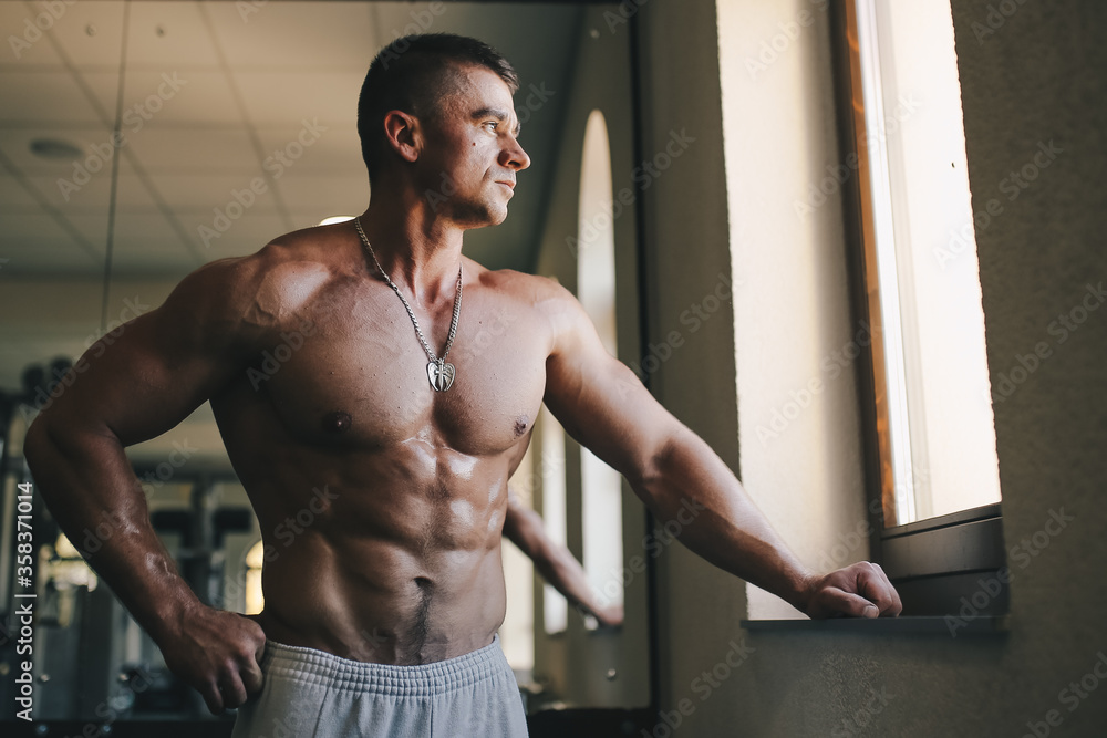 Handsome power athletic man on diet training pumping up muscles with ...