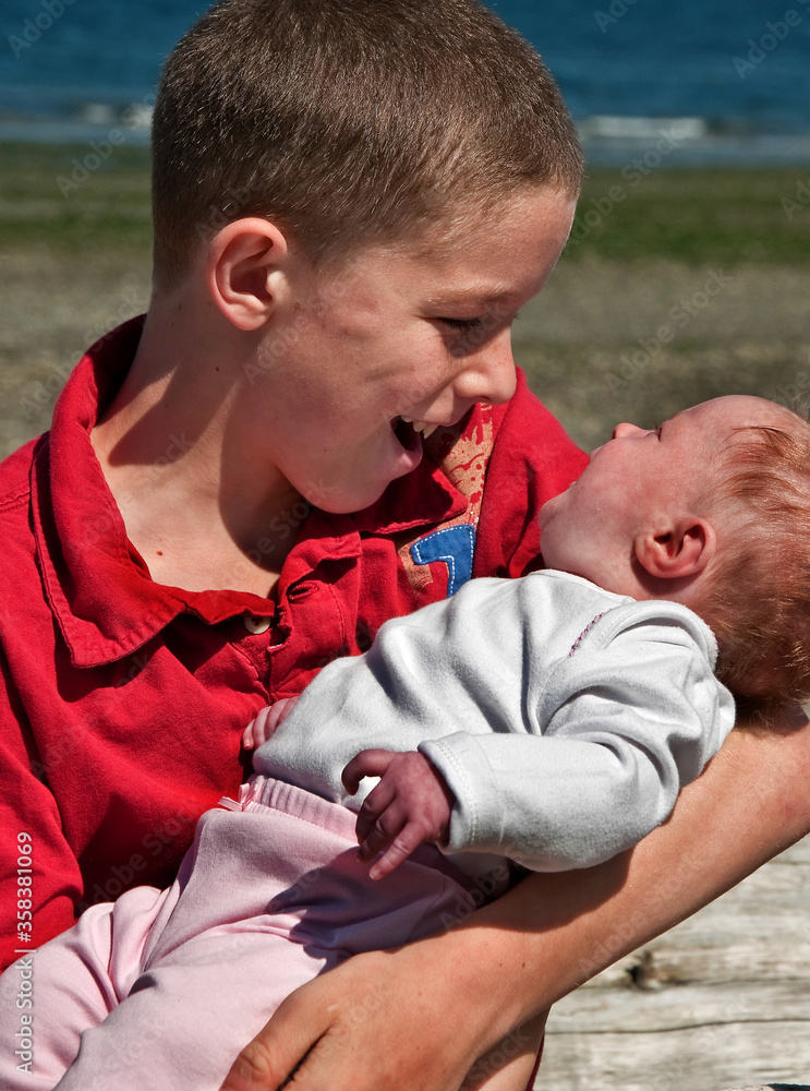 This shows a loving big brother holding and interacting with his ...