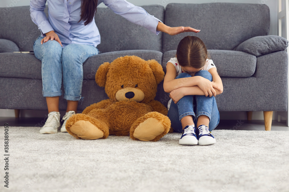 Upset little girl crying on floor near teddy bear while mother ...