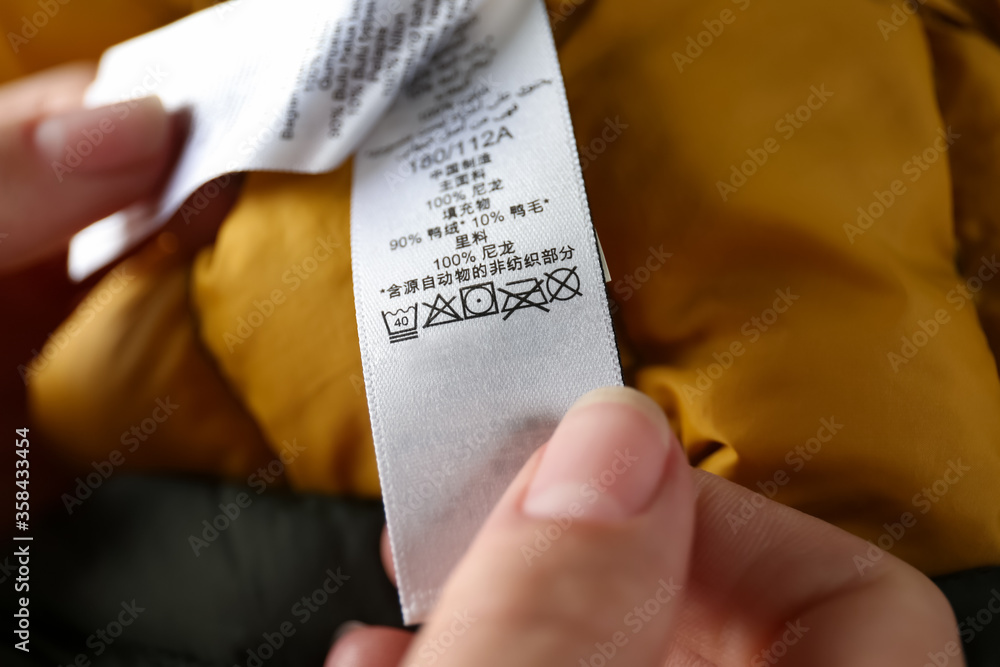 Woman reading clothing label with care symbols and material content on ...
