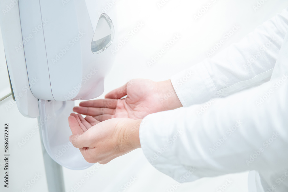 Foto de Male patient hands using automatic alcohol dispenser for ...