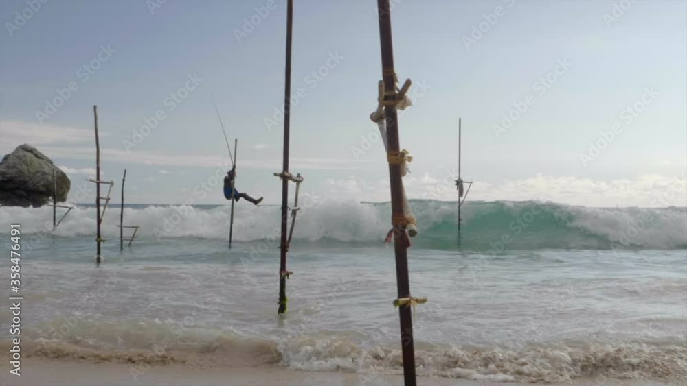 Low angle, slow motion slide of Sri Lankan stilt fisherman moving feet ...